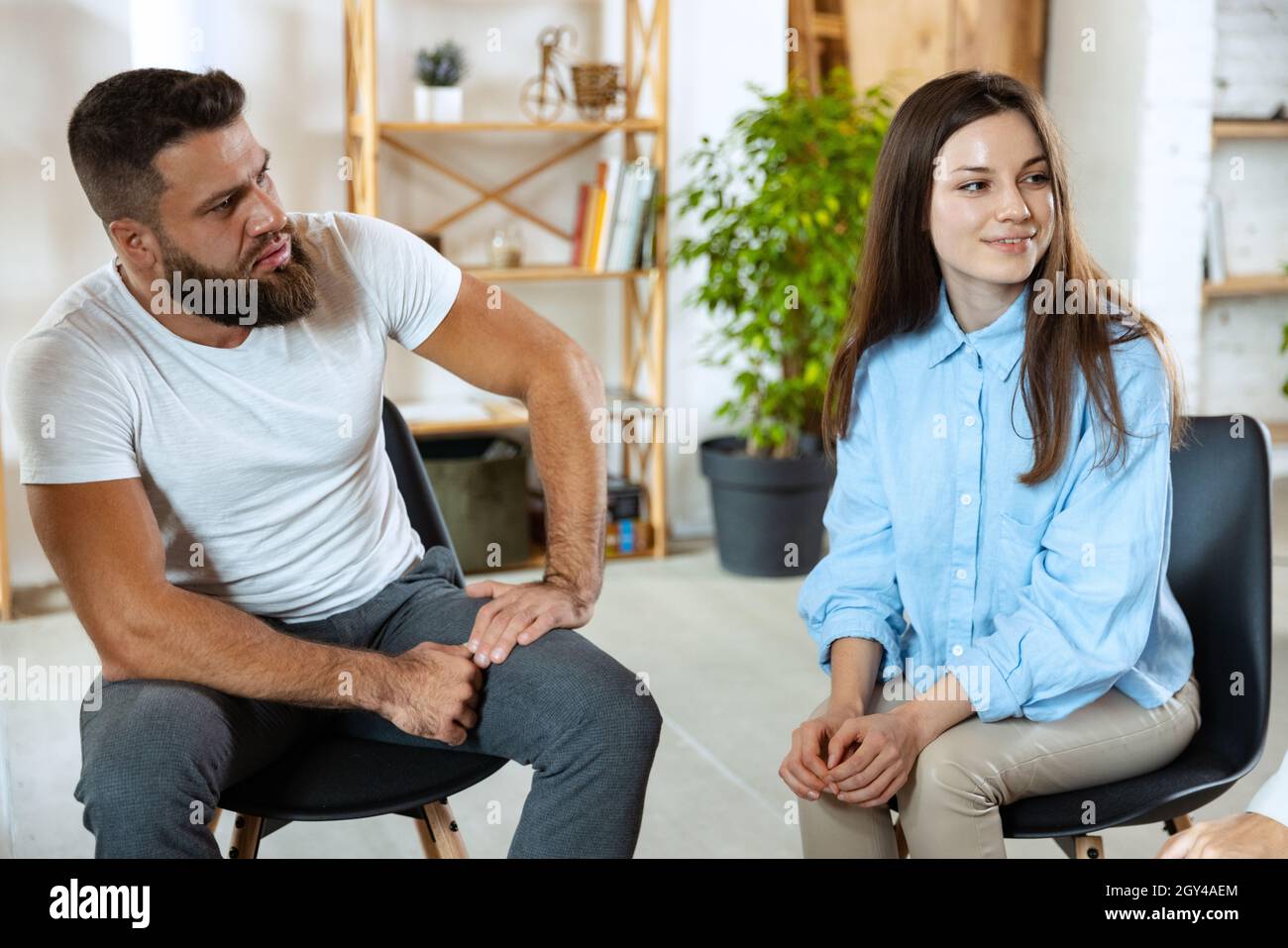 Two young people, married couple sitting in psychologist's office. Look ...