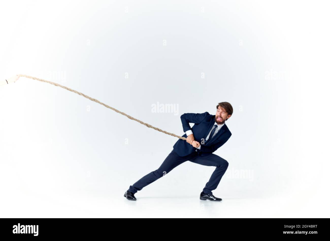 a man in a suit pulling a rope office manager teamwork Stock Photo - Alamy