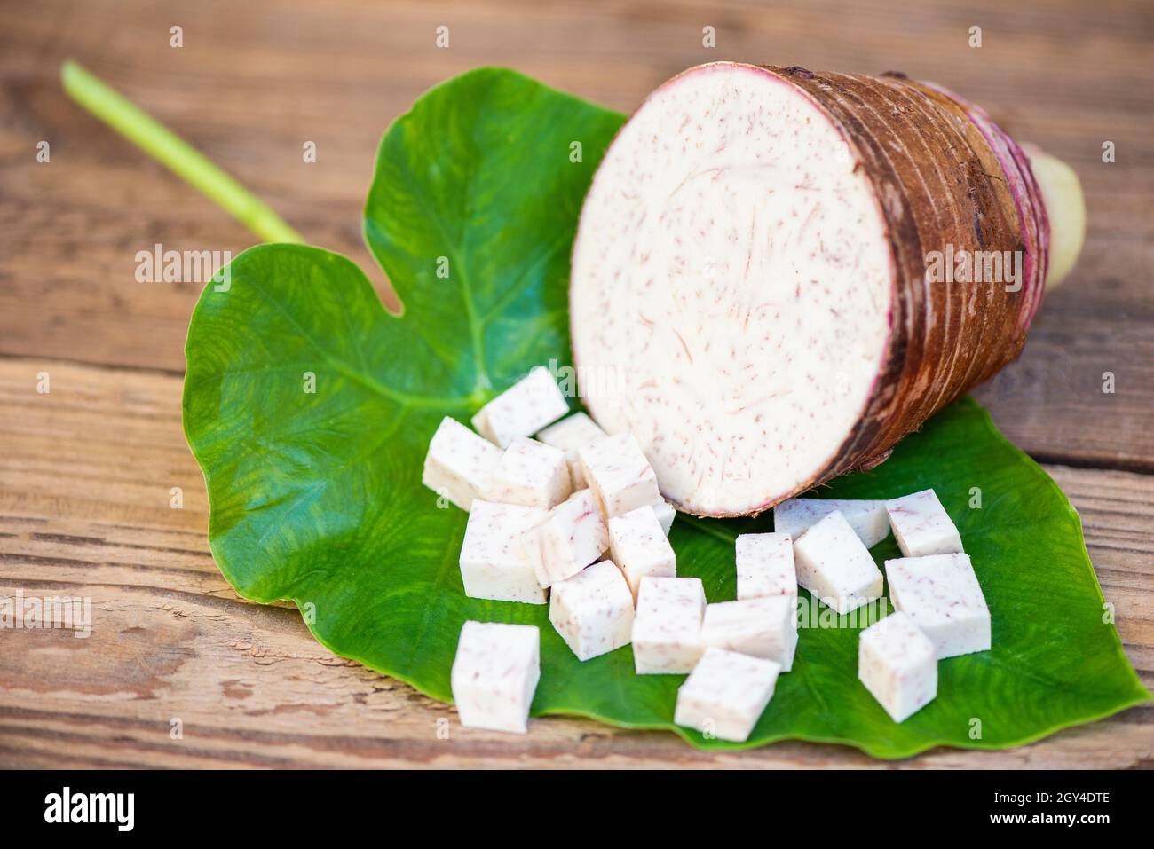Taro root with half and slice cubes on taro leaf and wooden background ...