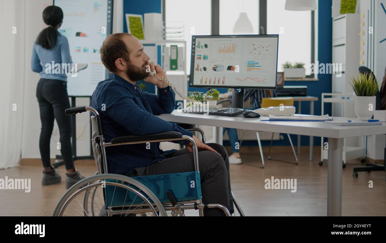 Entrepreneur with locomotor disabilities talking at phone with ...