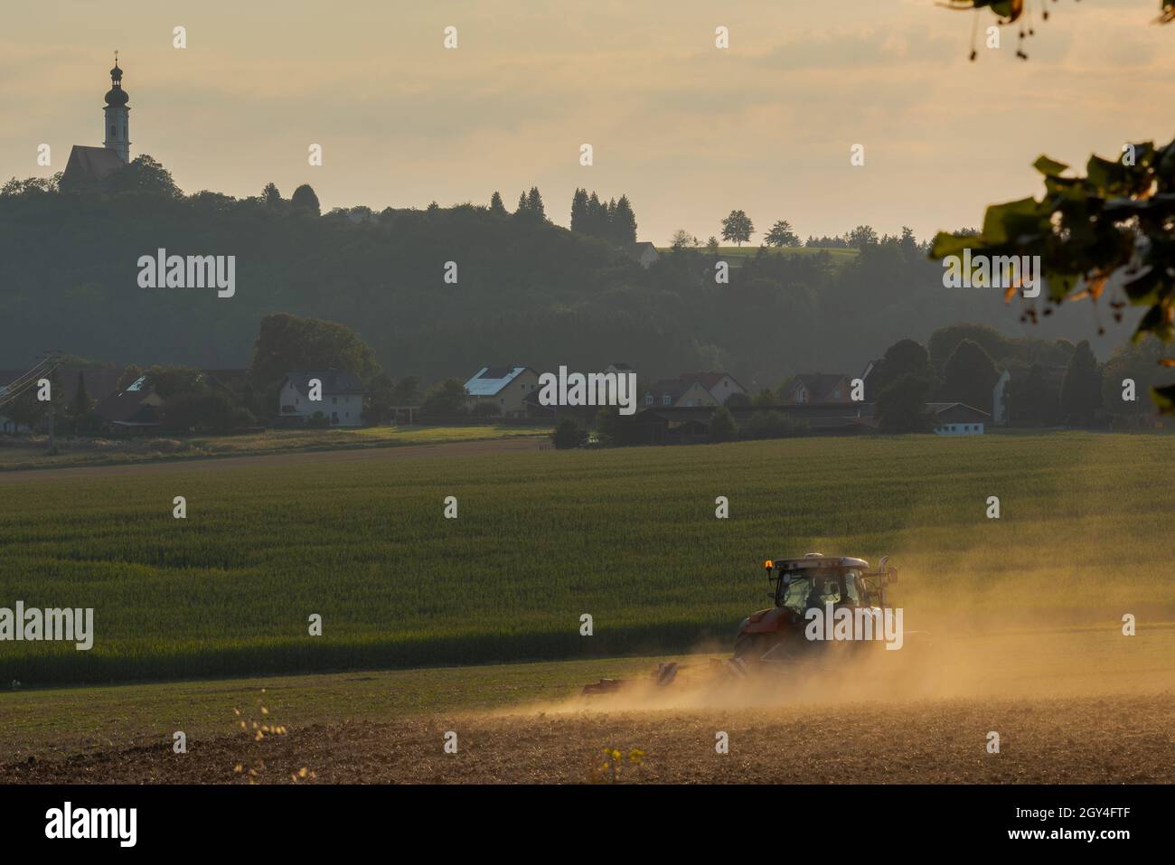 Typical Bavarian rural farm labor scene with tractor plowing field and ...