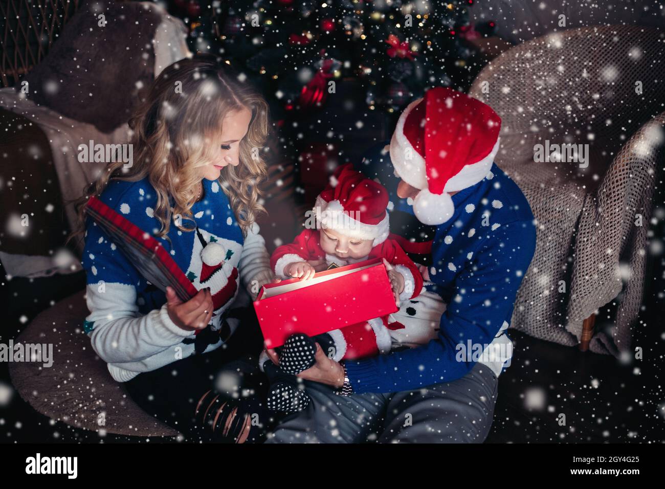 Santa baby opening present with parents Stock Photo - Alamy