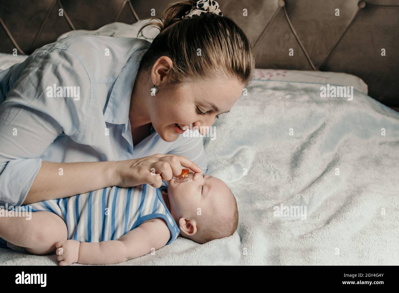 Portrait of young mother and her newborn baby boy cuddling in bed Stock ...