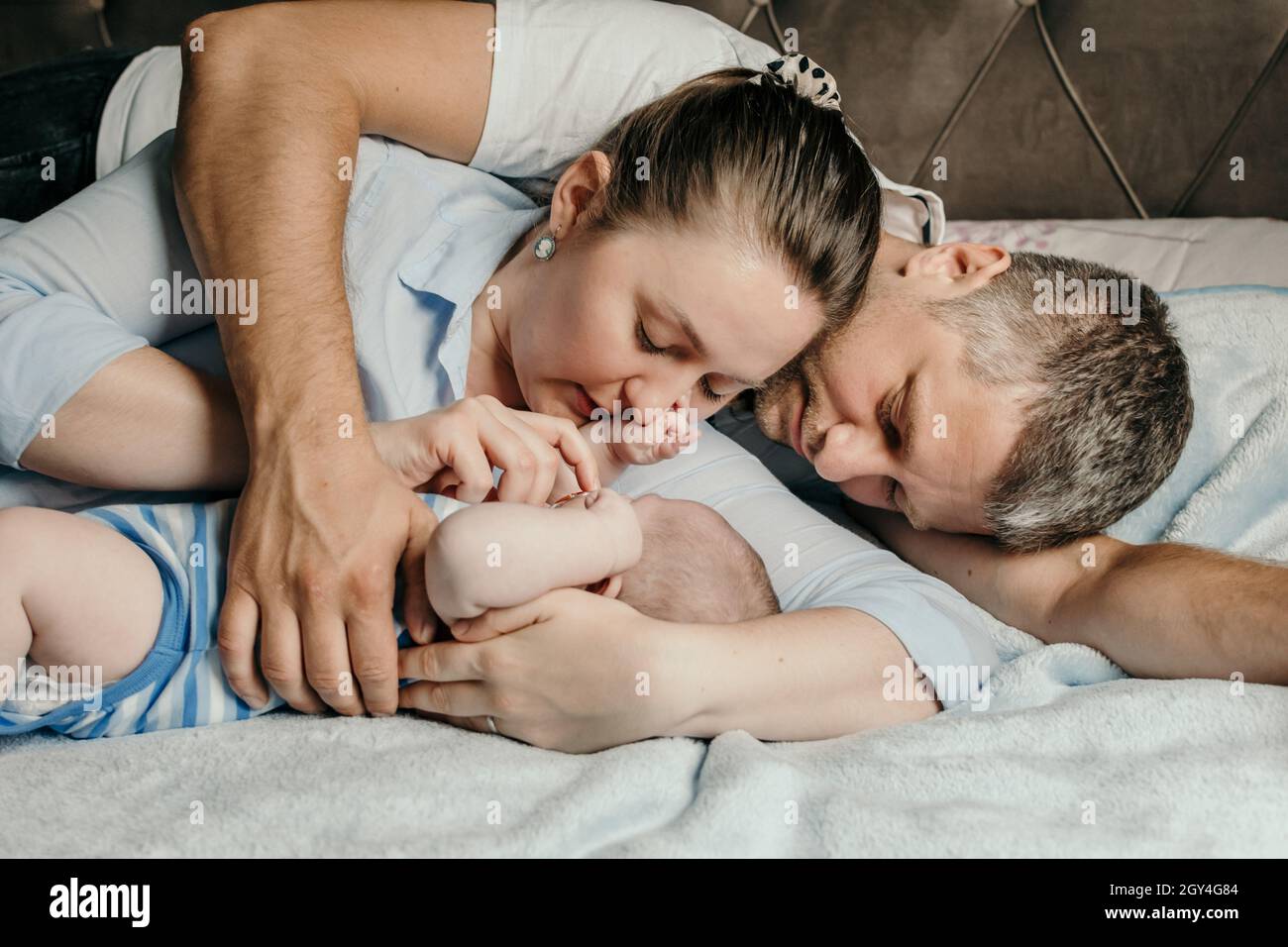 Portrait of young family with newborn baby boy cuddling in bed Stock ...