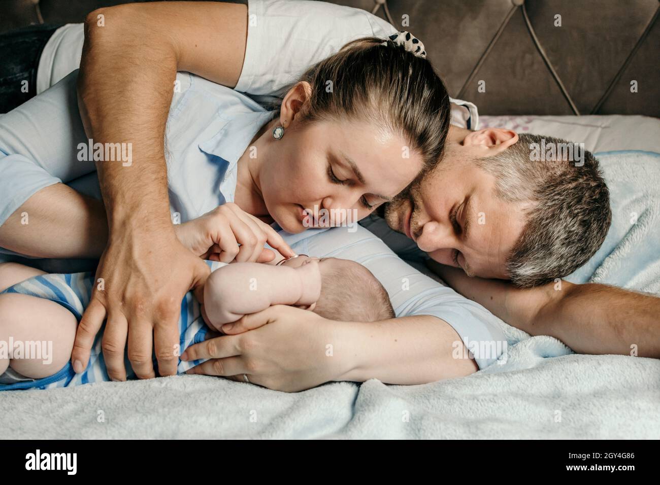 Portrait of young family with newborn baby boy cuddling in bed Stock ...