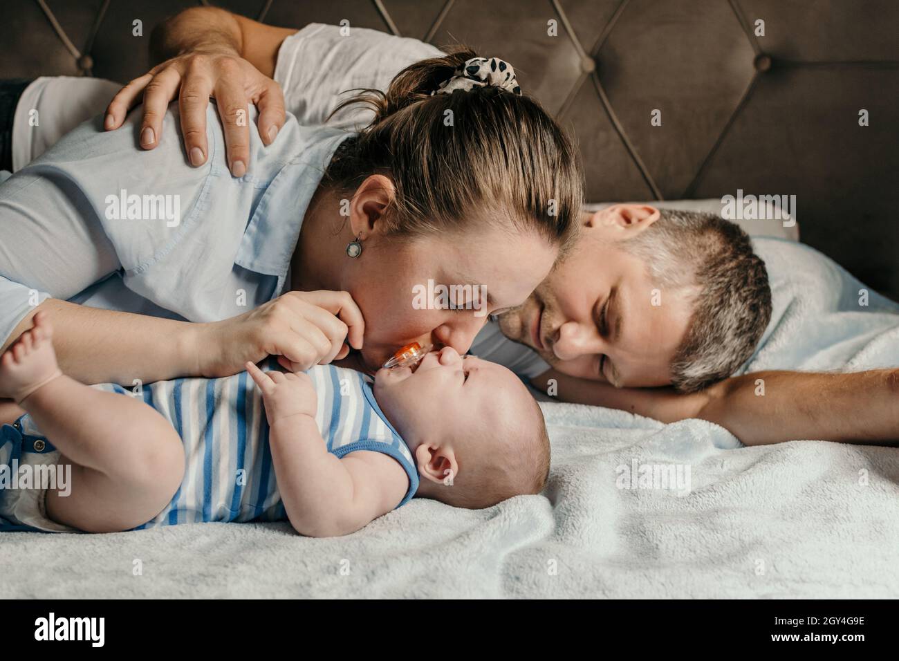 Portrait of young family with newborn baby boy cuddling in bed Stock ...