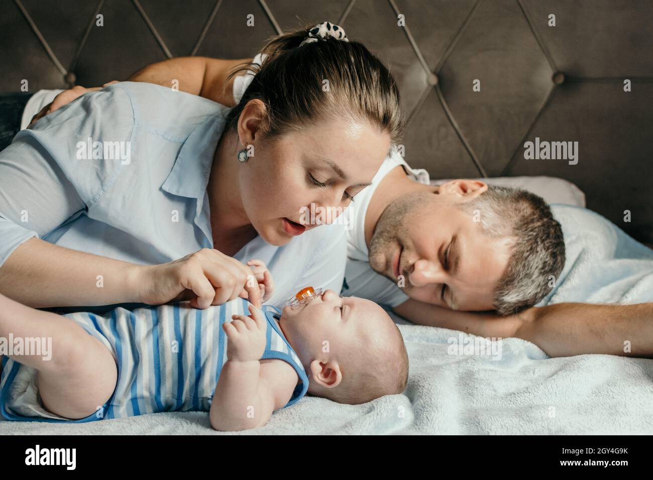 Portrait of young family with newborn baby boy cuddling in bed Stock ...