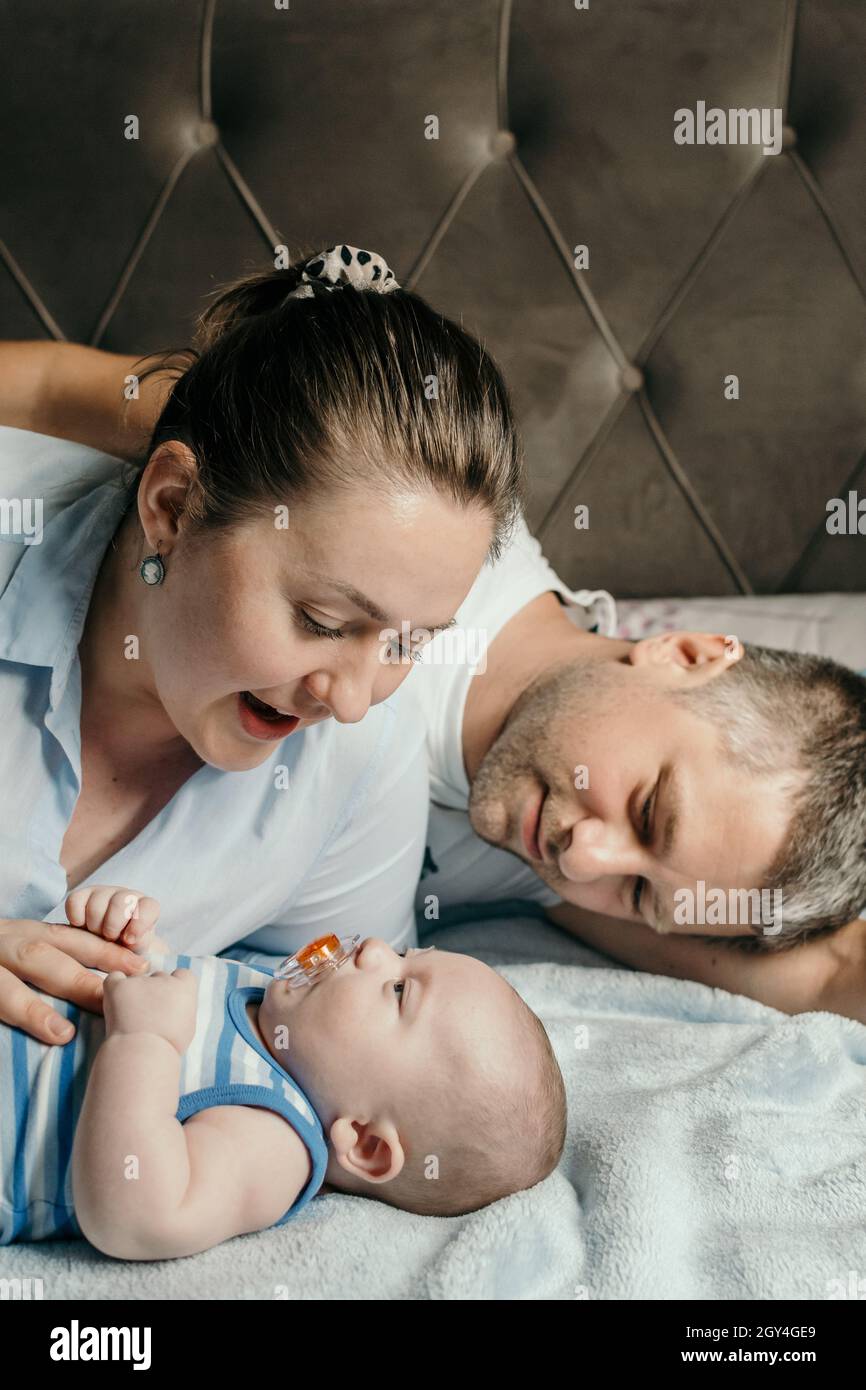 Portrait of young family with newborn baby boy cuddling in bed Stock ...