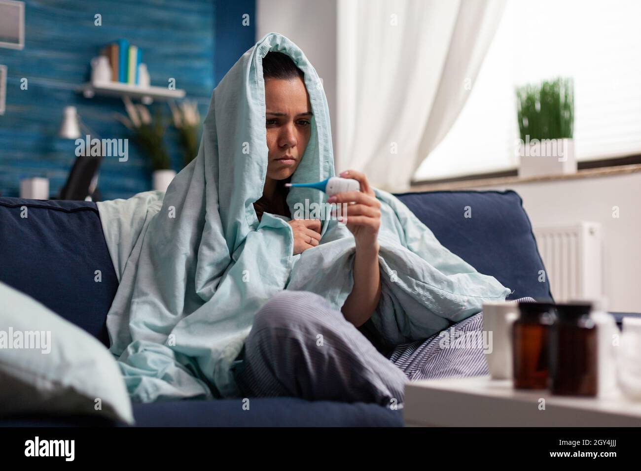 Caucasian woman measuring temperature ill at home with a thermometer ...