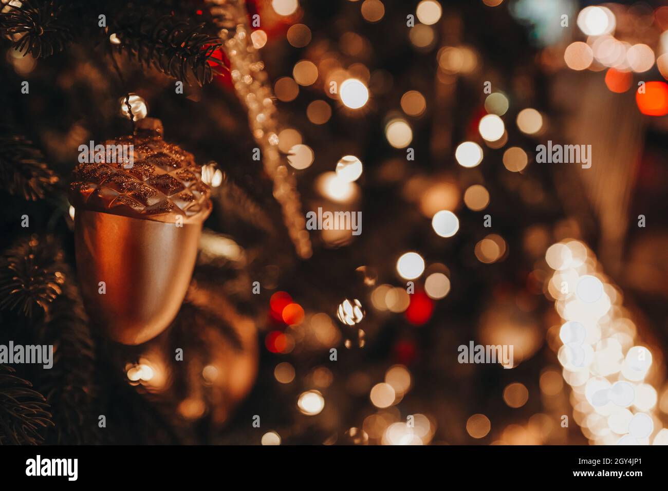 Festive background with beautiful Golden bokeh lights, Christmas toy acorn, fir branches ...