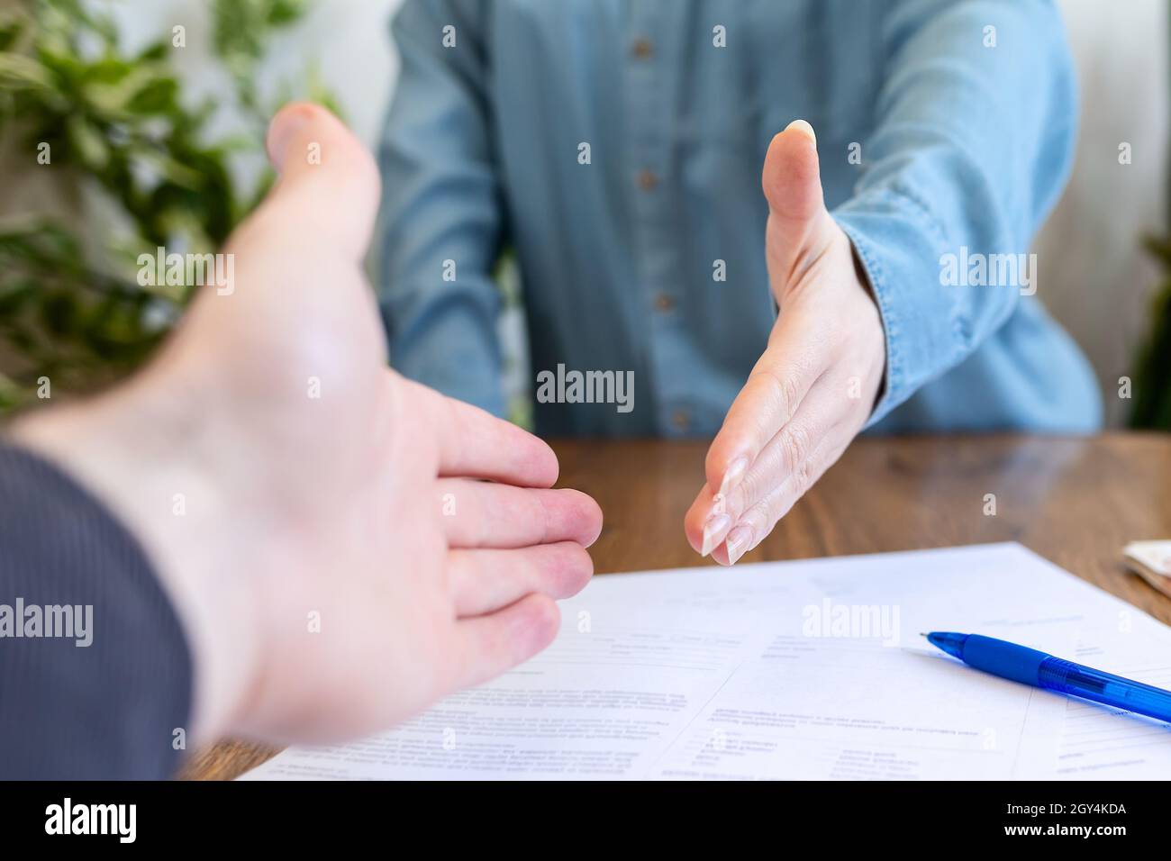 Realtor and buyer handshake. Close up. There are documents on the table ...