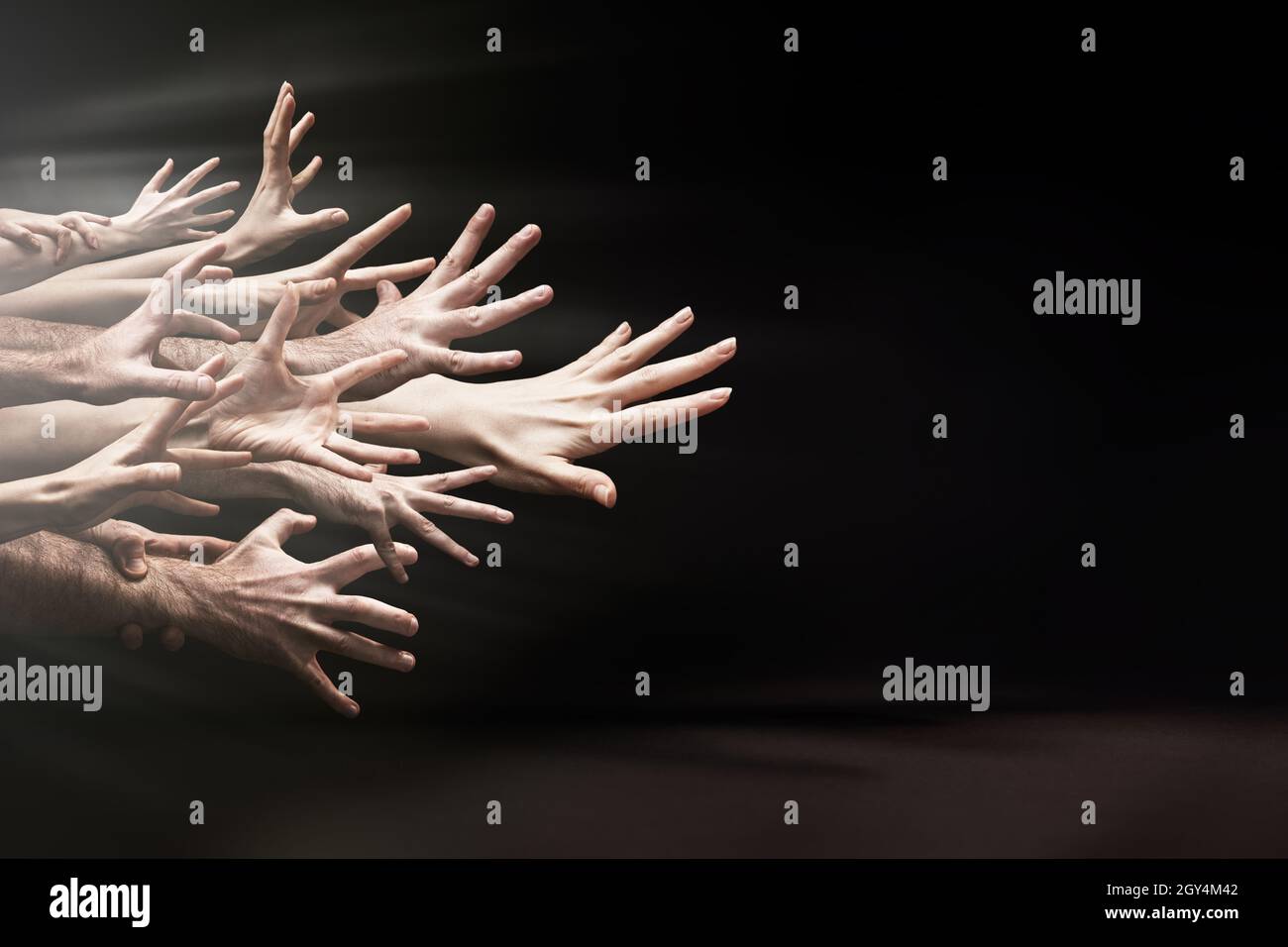 A lot of hands aggressively reaching forward. Black background. Copy ...