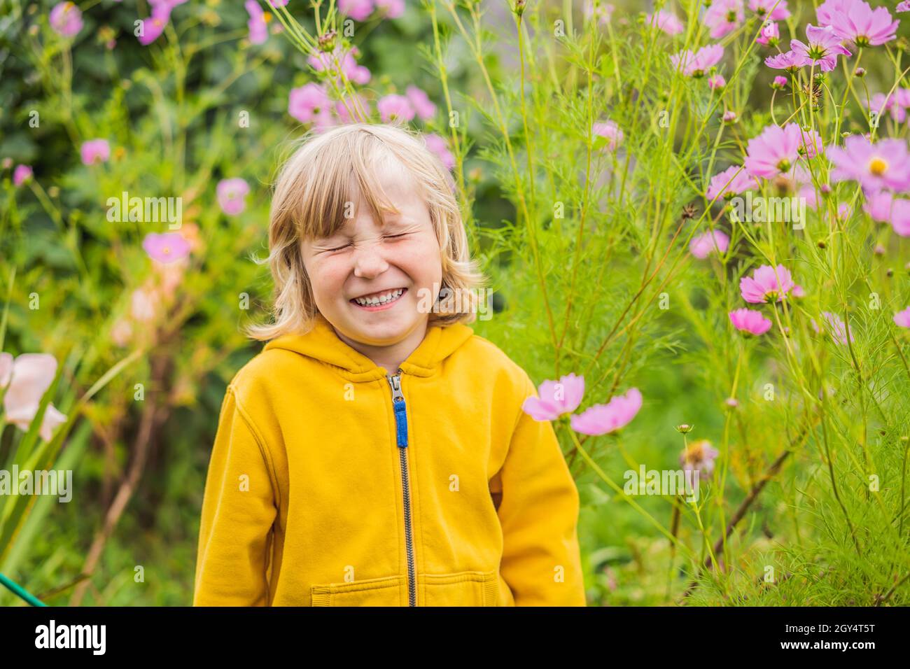 Boy enjoying pink flowers in the garden Stock Photo - Alamy