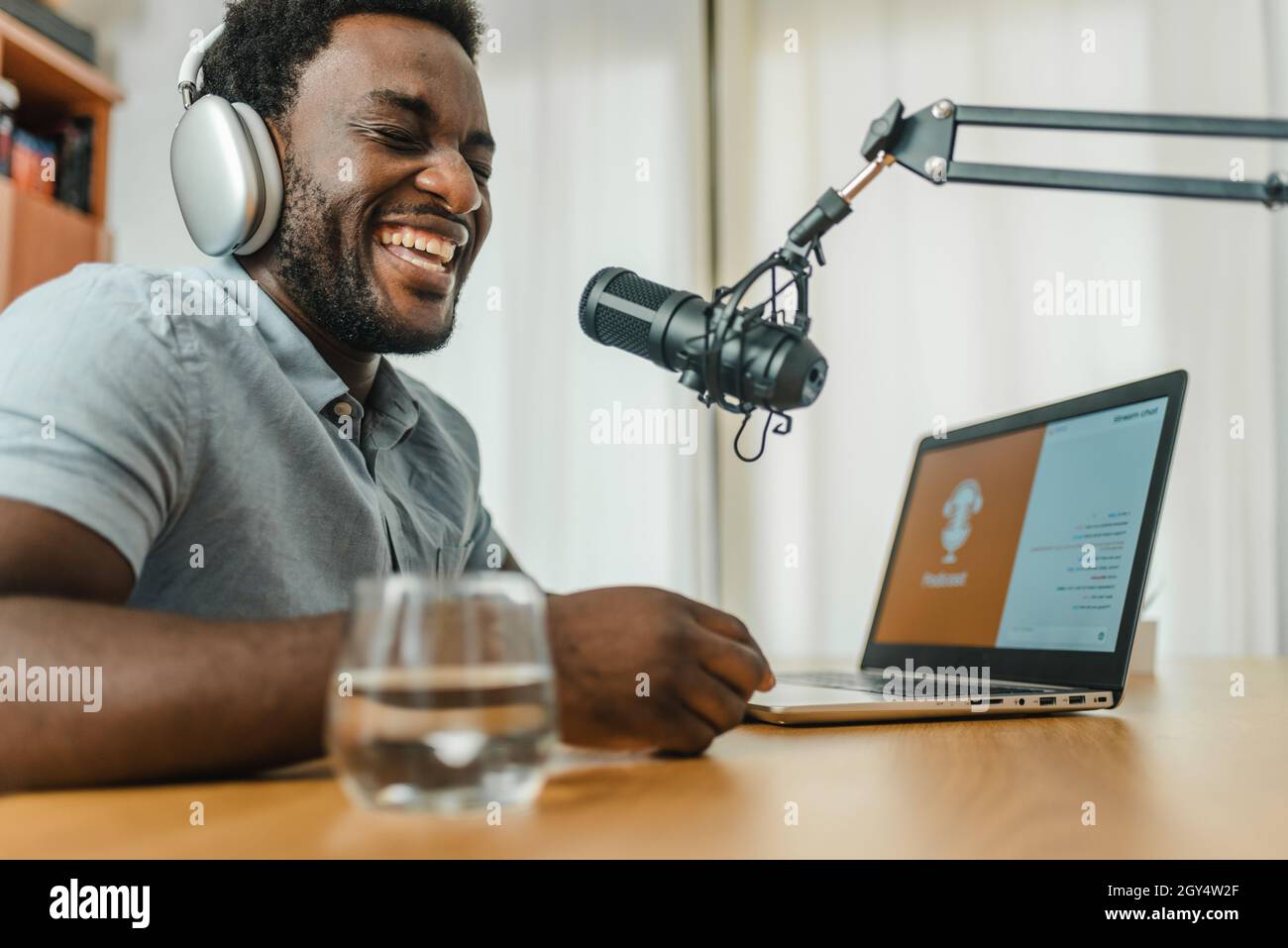 Black man in headphones recording podcast and laughing Stock Photo - Alamy