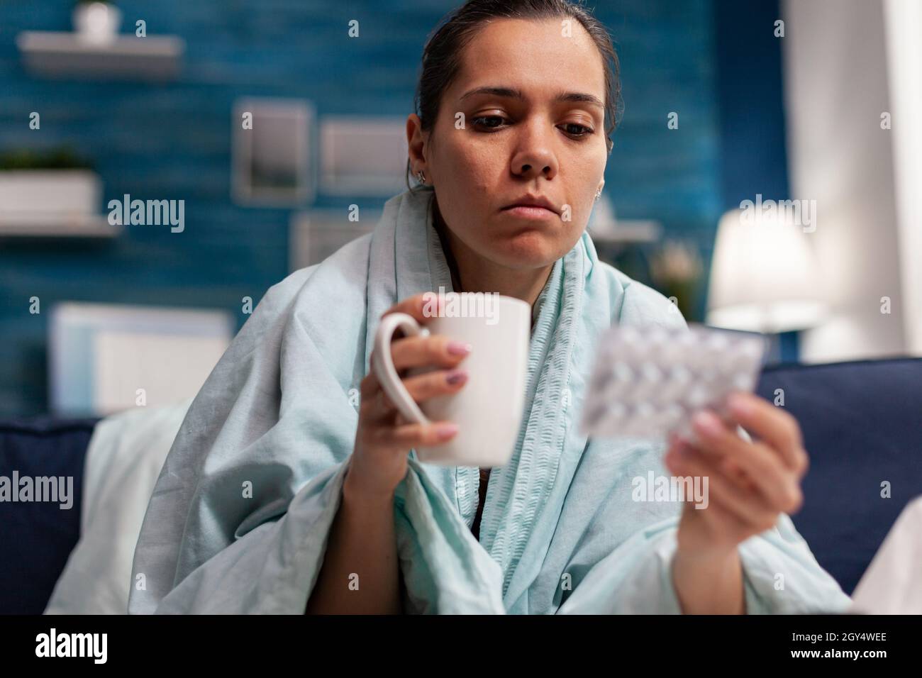 Young sick woman with infection symptoms at home using treatment ...