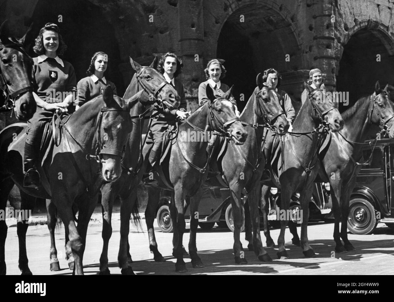 A group of young women on horseback stands in front of the Colosseum in ...