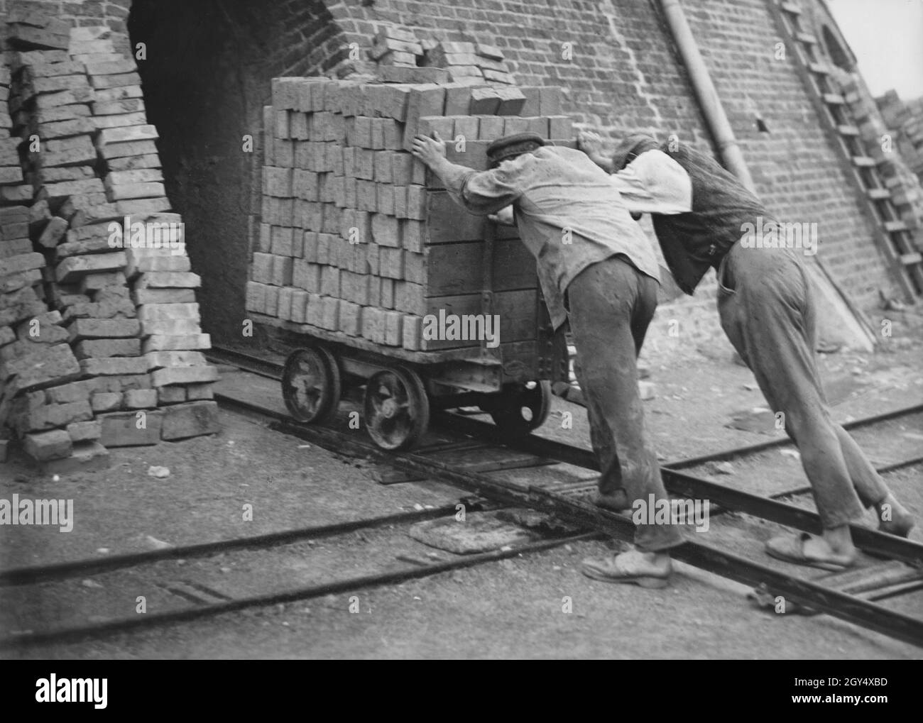 Workers push a cart of bricks into the kiln for firing . [automated ...