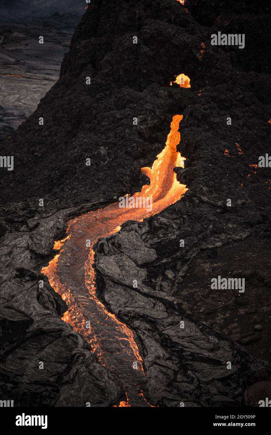Mesmerizing vertical shot of lava flowing over the bumpy mountain Stock ...
