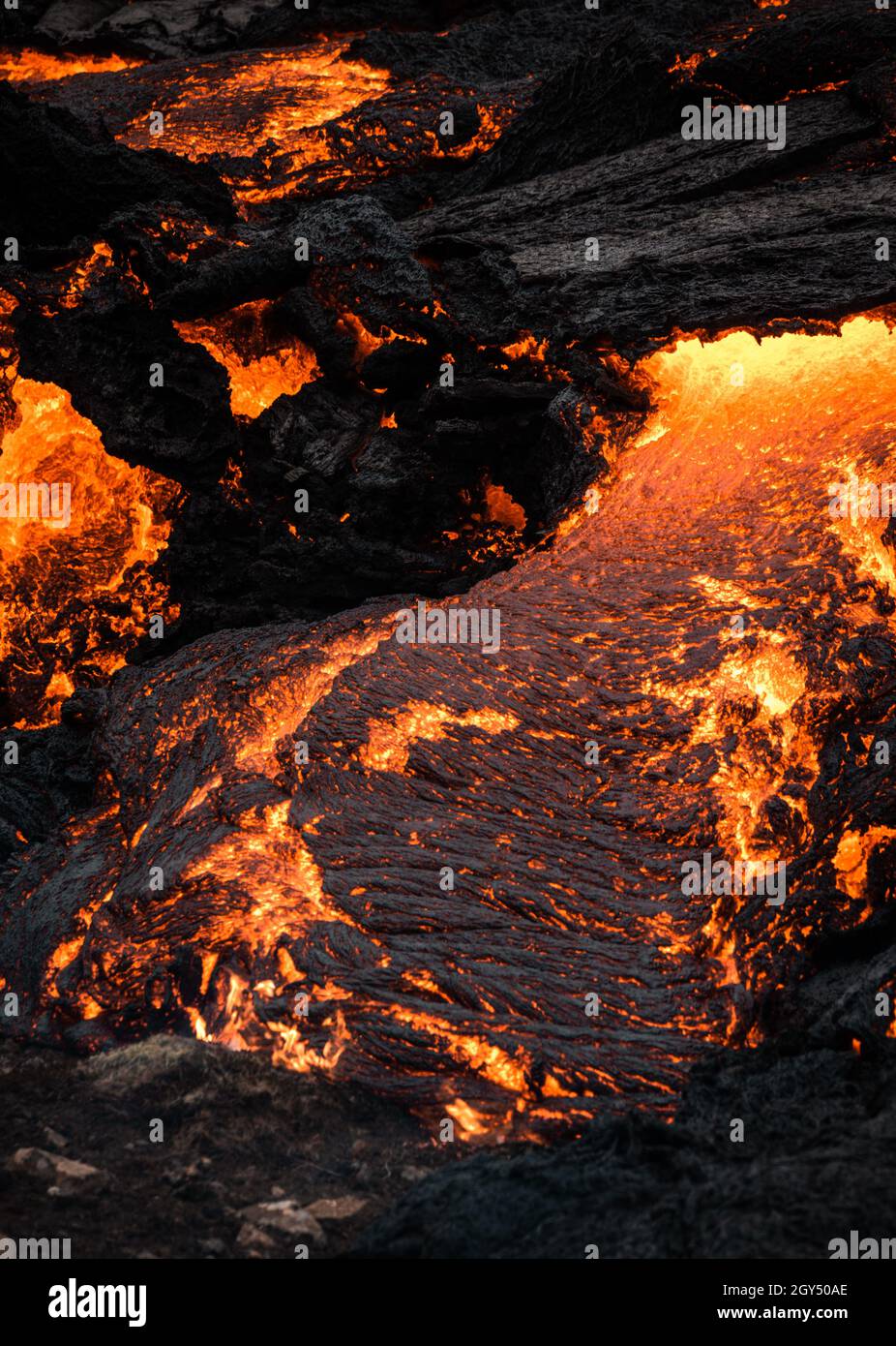Mesmerizing vertical shot of lava flowing over the bumpy mountain Stock ...