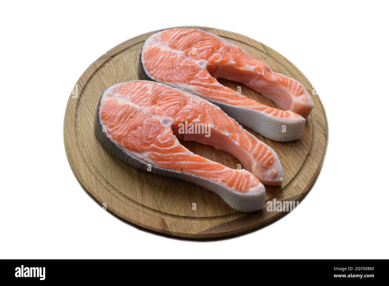 Two raw red fish steaks lie on a brown wooden cutting round board. On ...