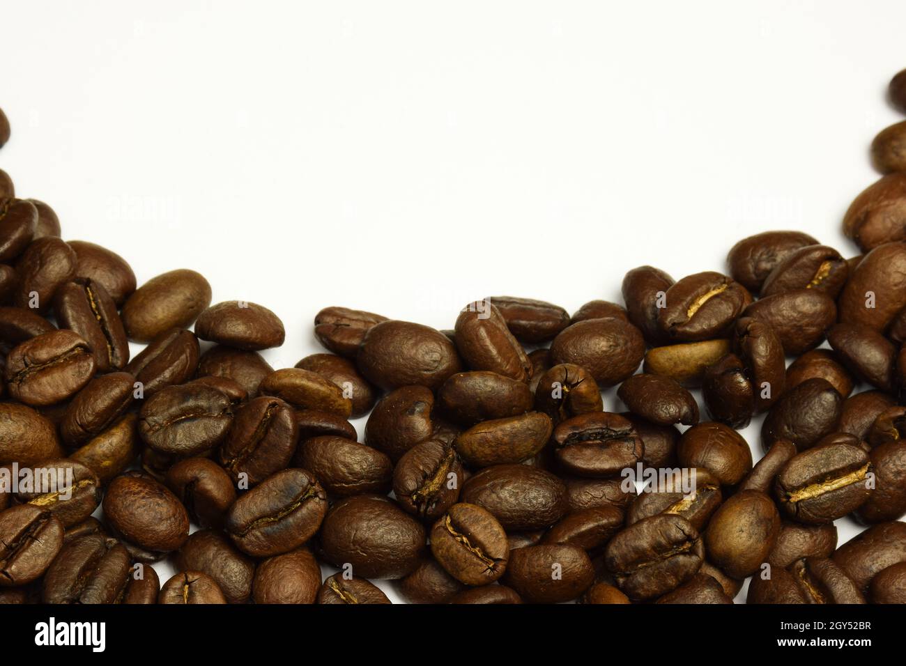 Roasted coffee grains scattered in a semicircle on a white background ...
