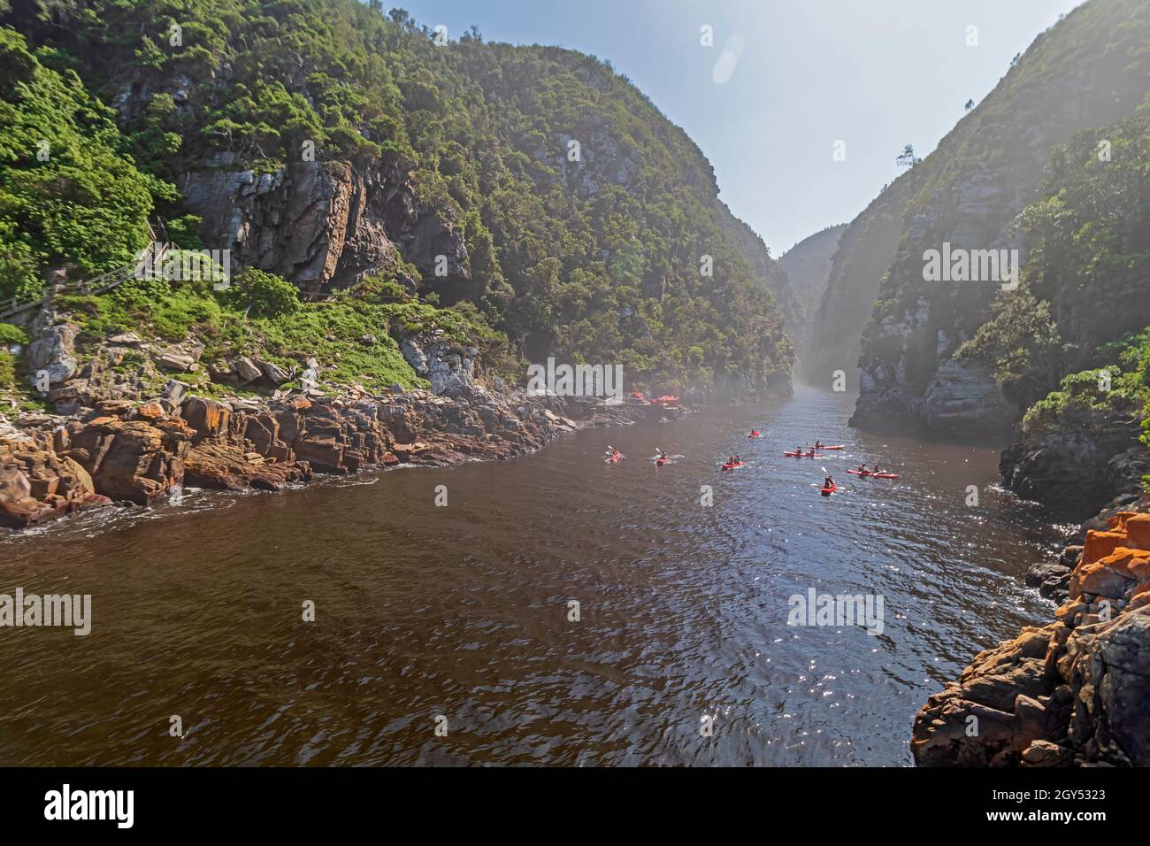 A view of Storms River Gorge with a group of kayakers in the river at ...