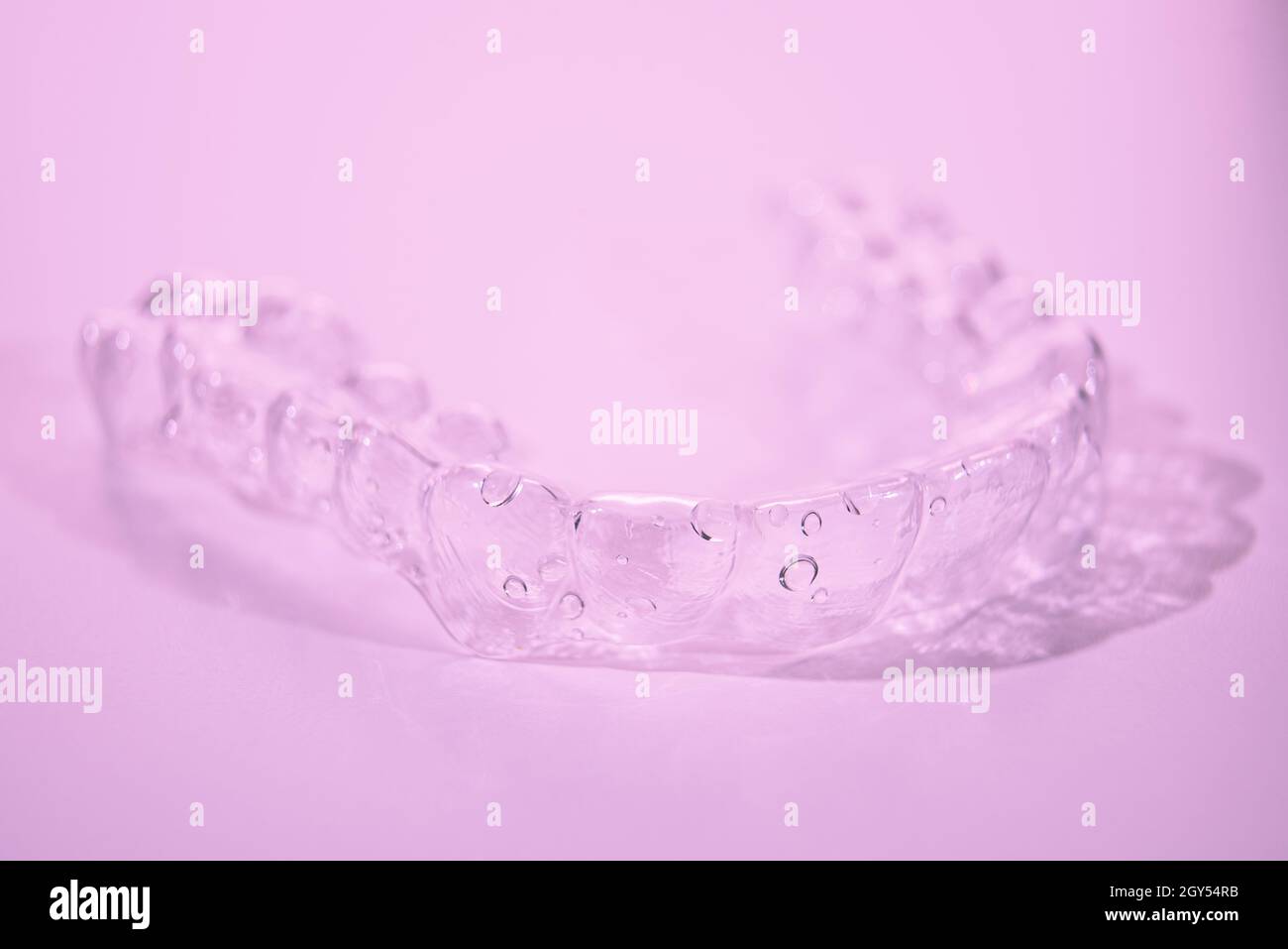 Invisible aligner teeth retainers on a pink background Stock Photo - Alamy