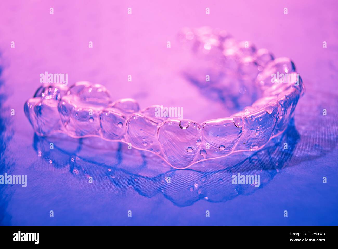 Invisible aligner teeth retainers on a pink background Stock Photo - Alamy