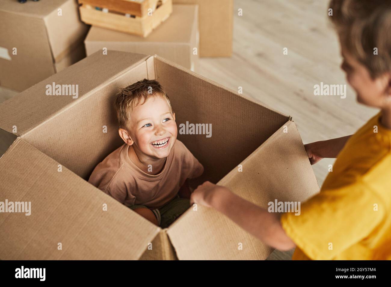 High angle portrait of happy smiling boy sitting in cardboard boxes and ...