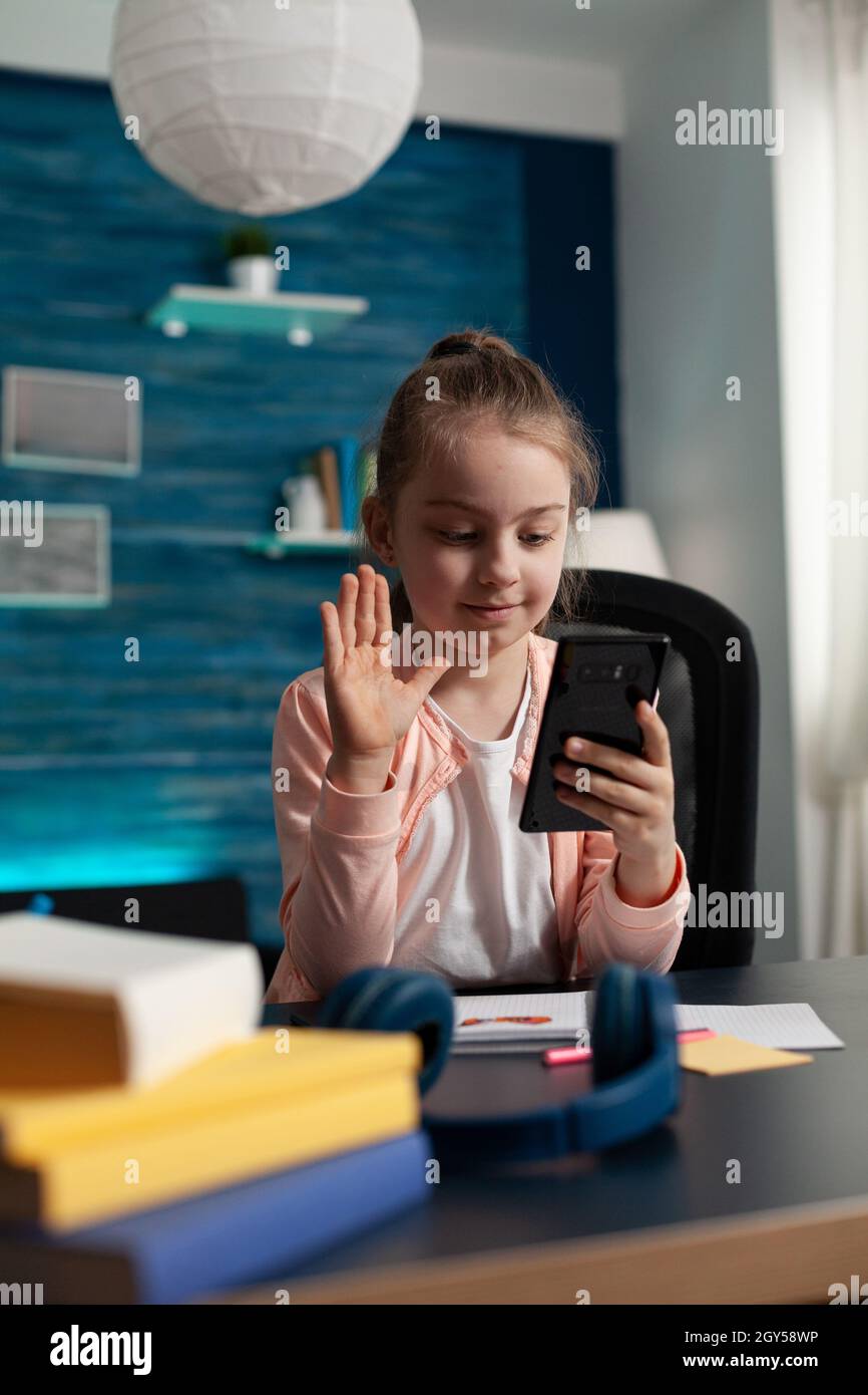 Schoolchild greeting remote friend during online videocall meeting ...