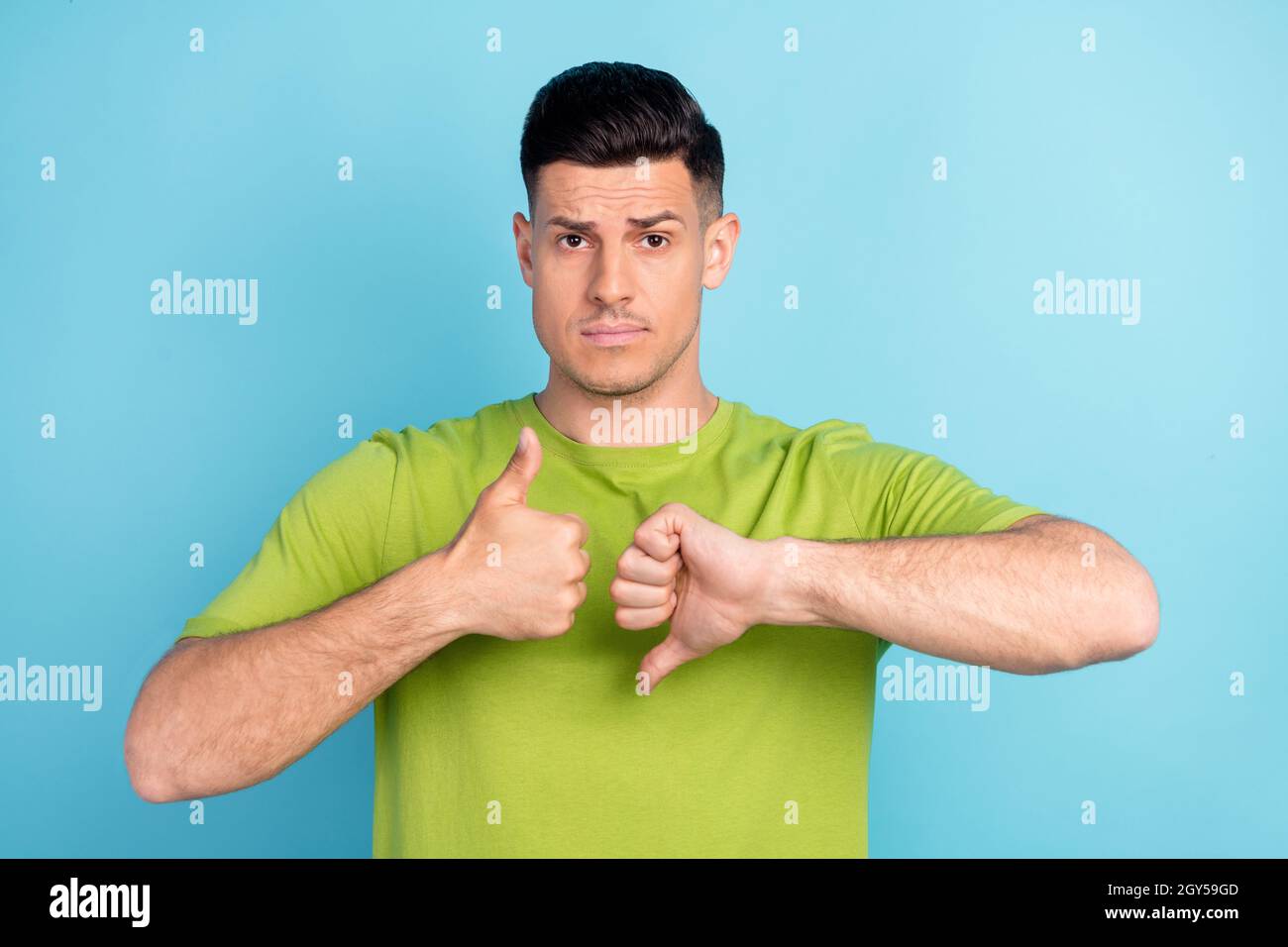 Photo of young unhappy man make fingers thumb up down choose uncertain ...