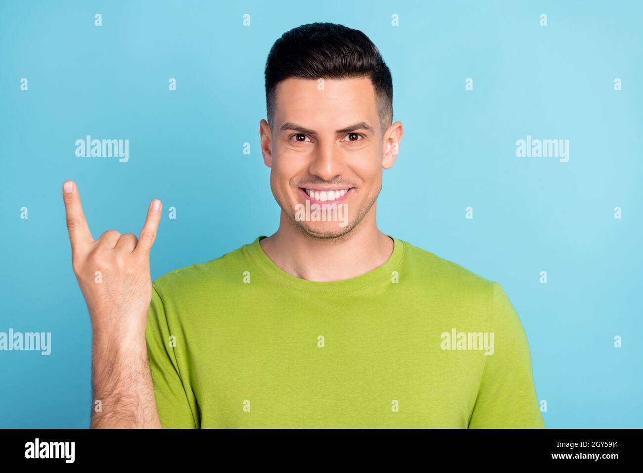 Photo of charming happy positive young man make fingers horned sign ...