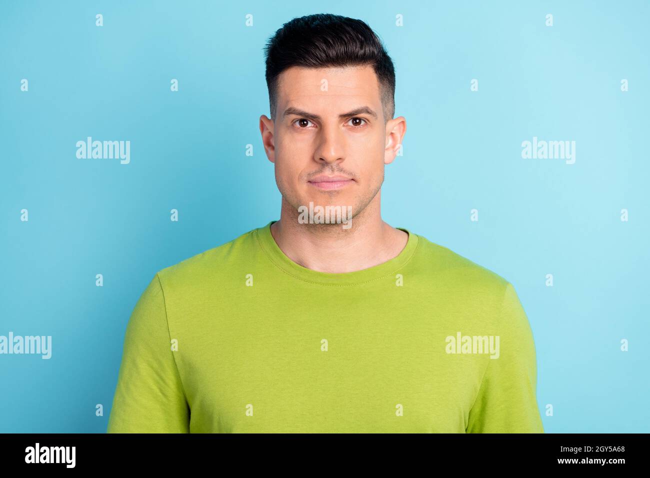 Photo portrait serious man in green t-shirt isolated pastel blue color ...