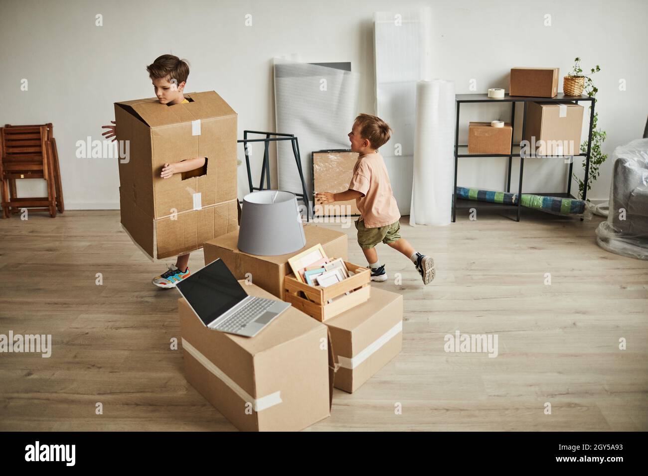 Side view portrait of two brothers wearing cardboard boxes and playing ...