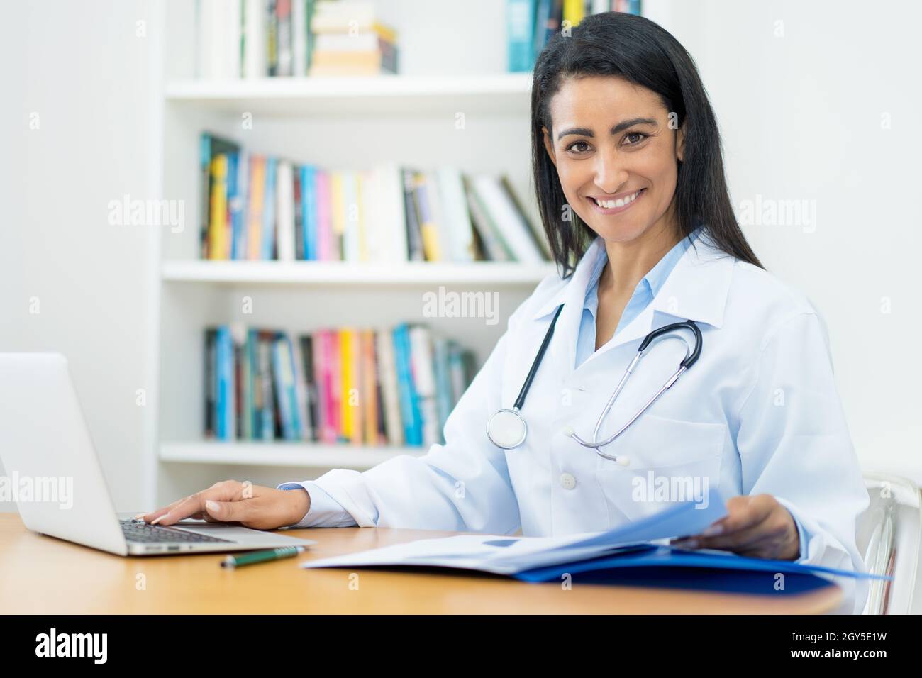 Beautiful latin american female gynecologist at desk at work at ...