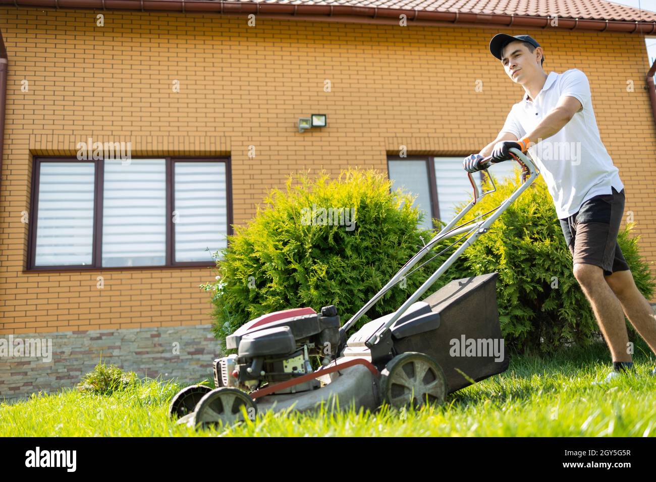 Man with lawn mower takes care of his lawn in his backyard Stock Photo ...