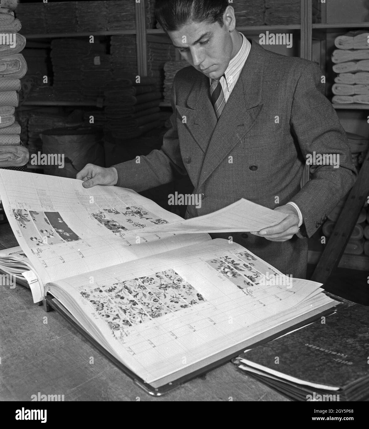 Der Lehrling sucht im Musterbuch nach Stoffmustern, Deutschland 1940er ...