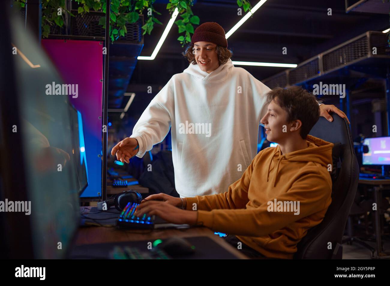 Two young gamers talking at the monitor in gaming club. Virtual ...
