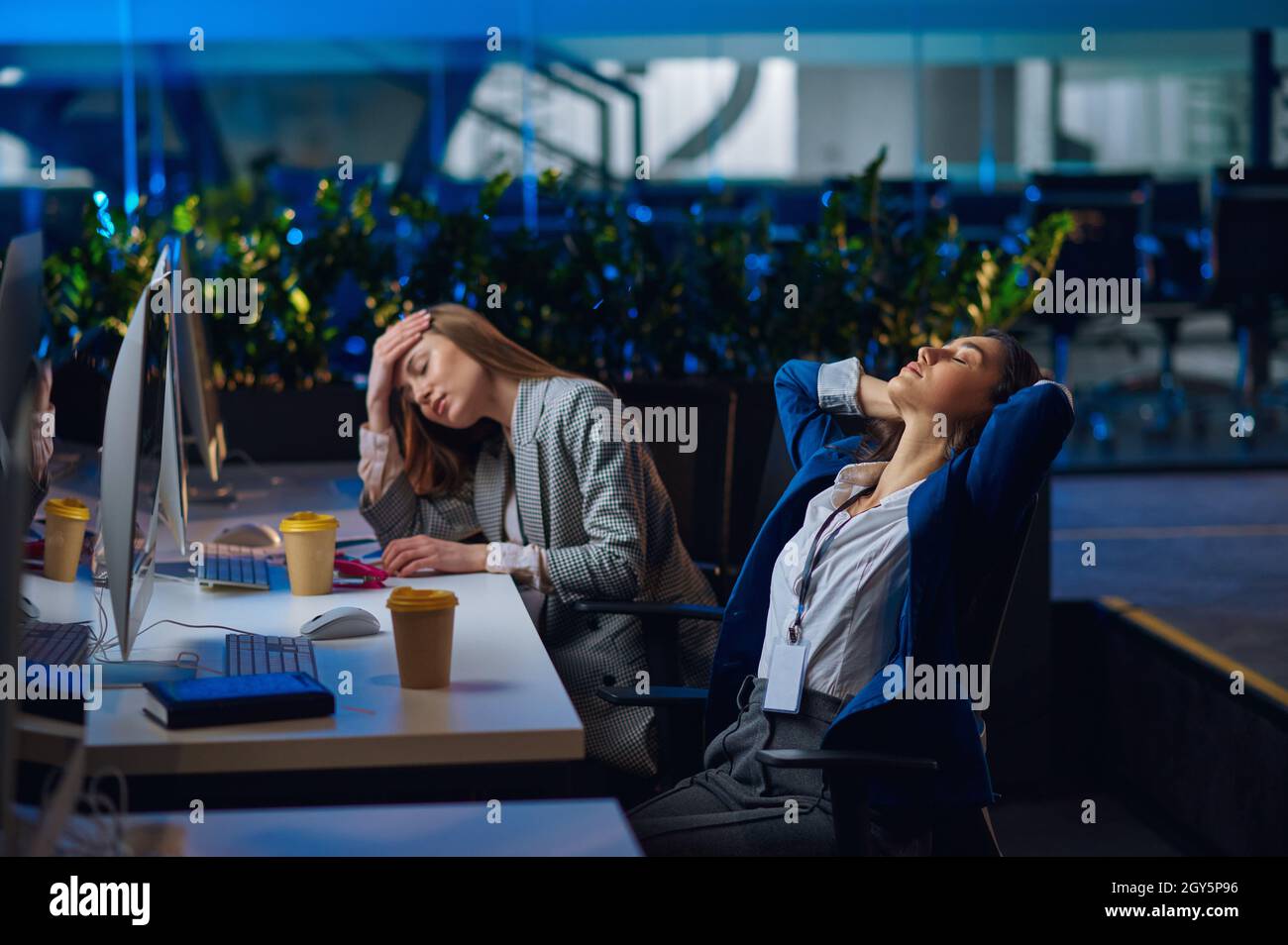 Tired women works on computers in night office. Sleepy female ...