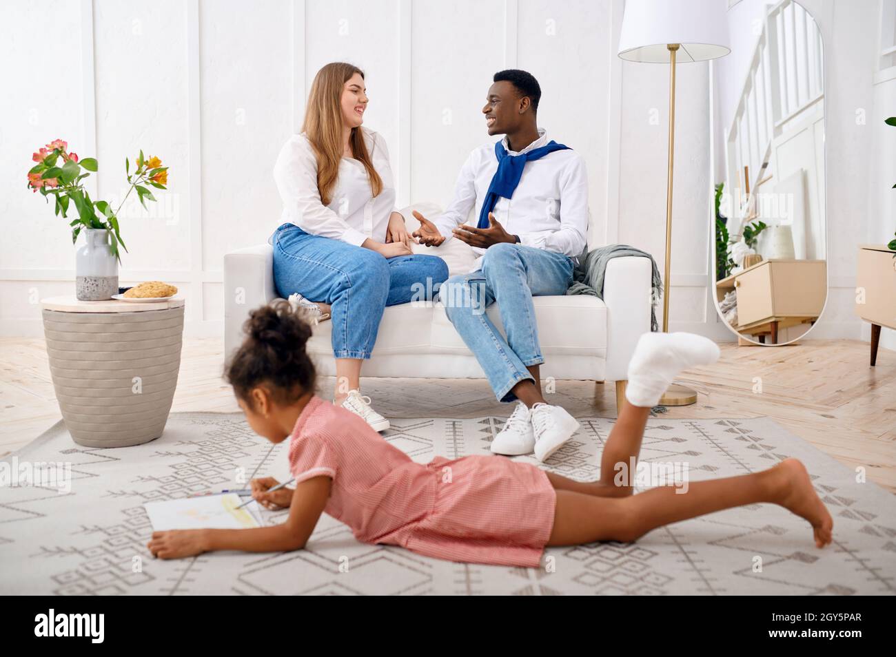 Happy family relaxing in living room. Mother, father and their little ...