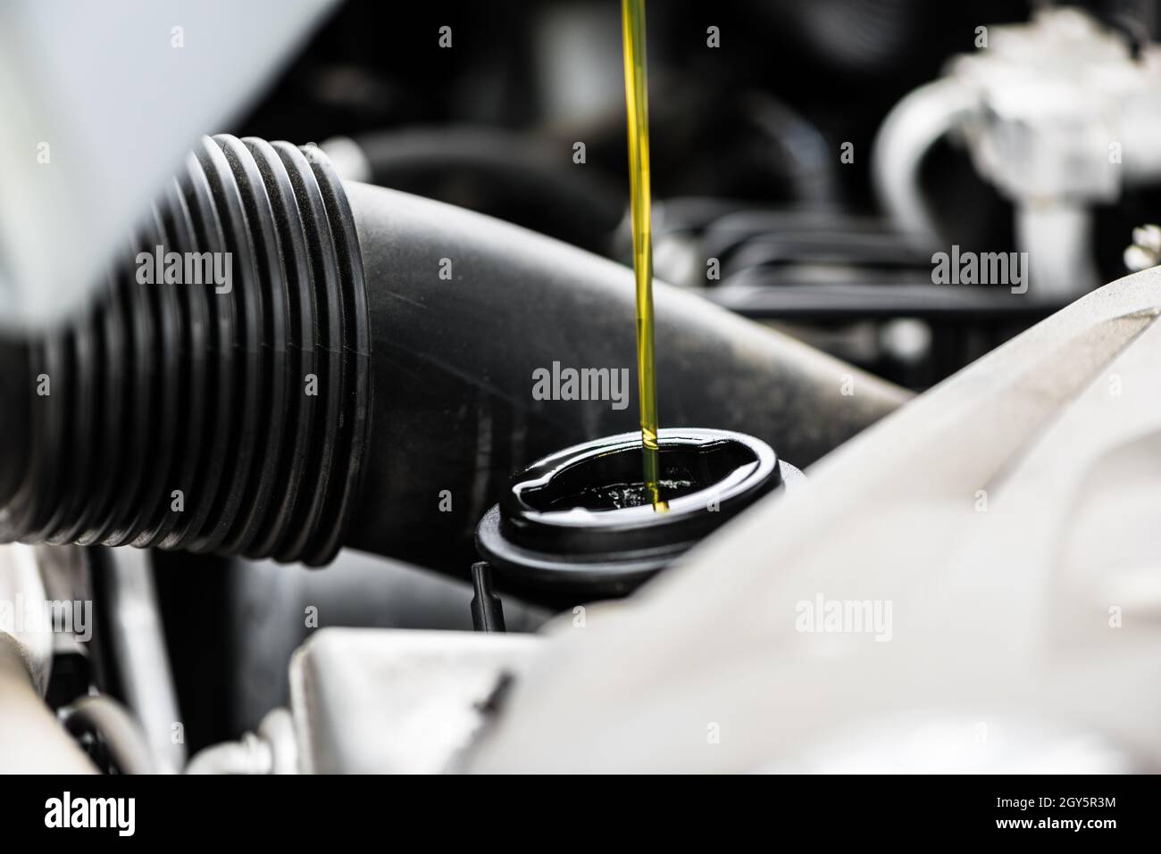 Woman putting oil into the engine of her car having opened the bonnet ...