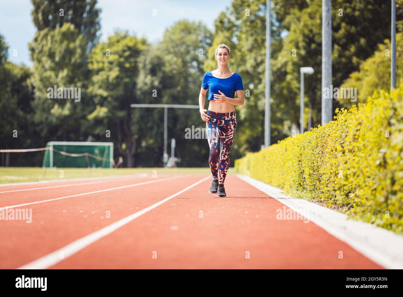 Blonde fit female athlete on summer day running on track Stock Photo ...