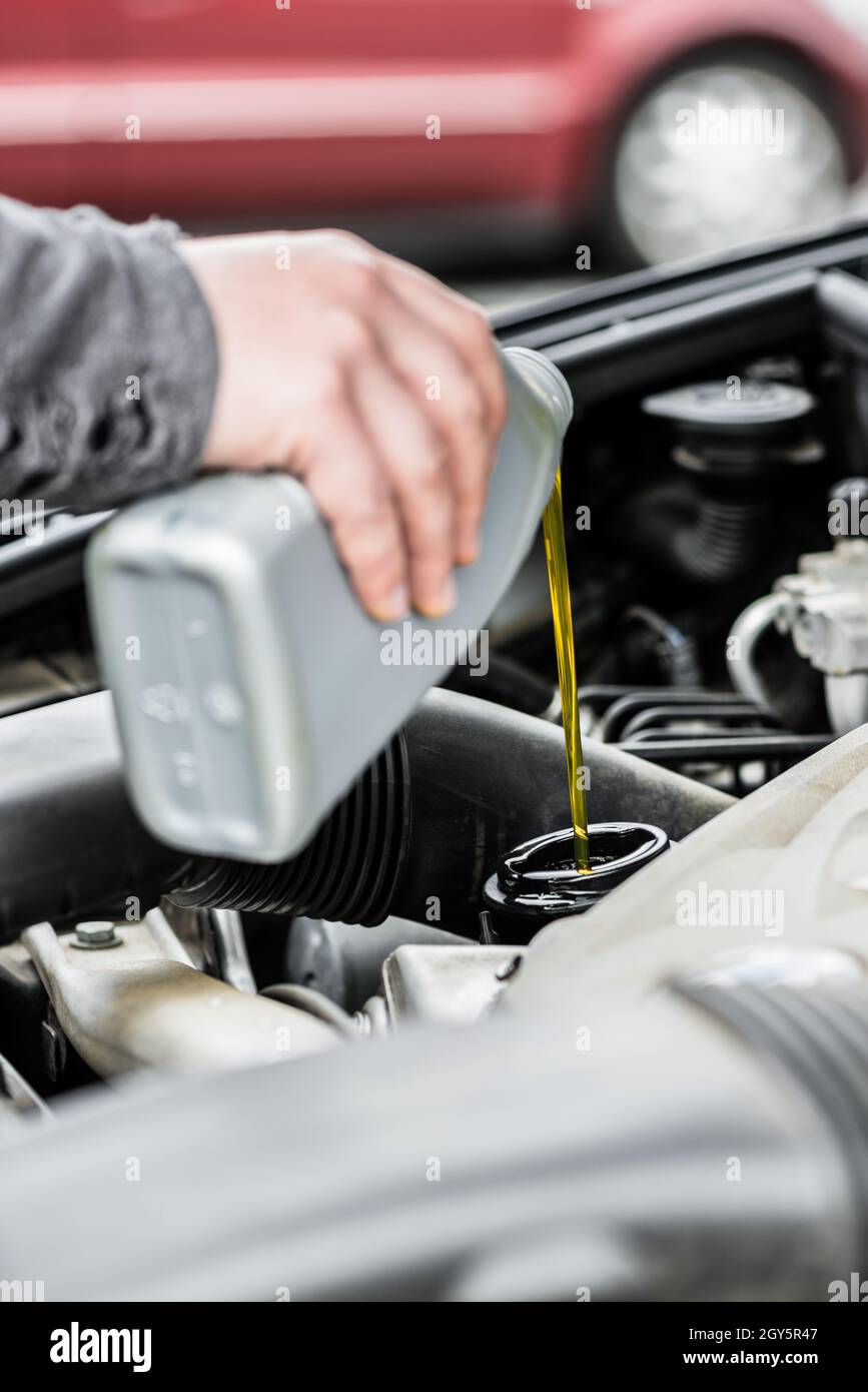 Woman putting oil into the engine of her car having opened the bonnet ...