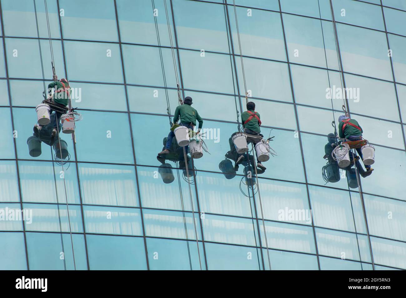 Many men are hanging down cleaning the glass skyscrapers Stock Photo ...