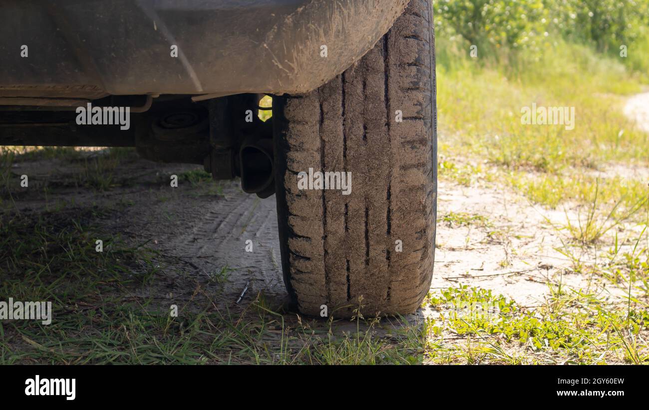 Passenger side of a white modern car on a dirt road, rear view of the ...