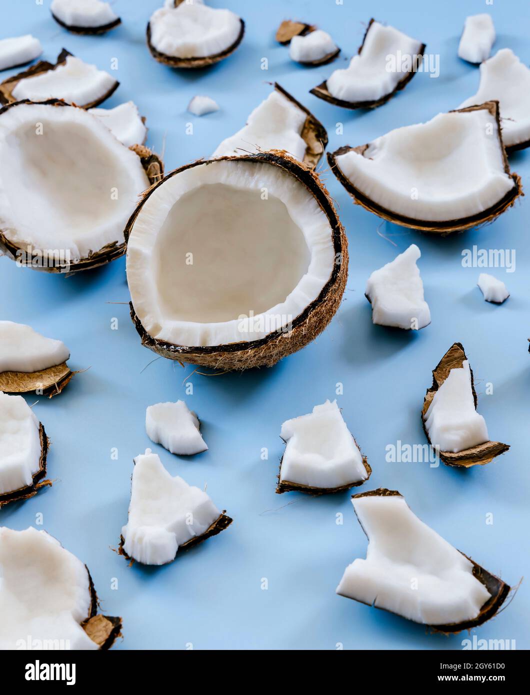 Broken coconut shells on a blue background Stock Photo - Alamy