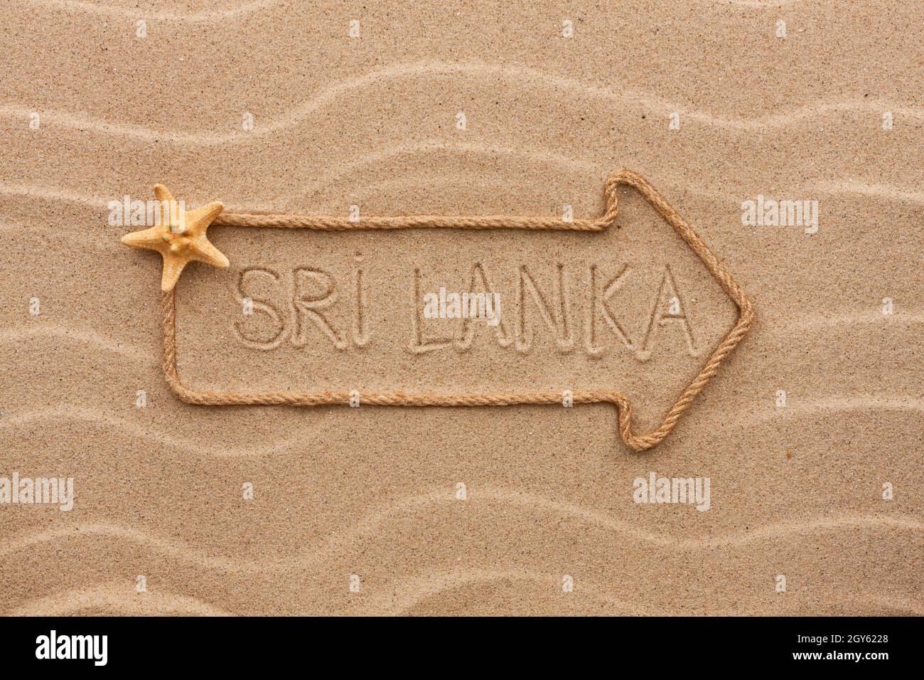 Arrow made of rope and sea shells with the word Sri Lanka on the sand ...