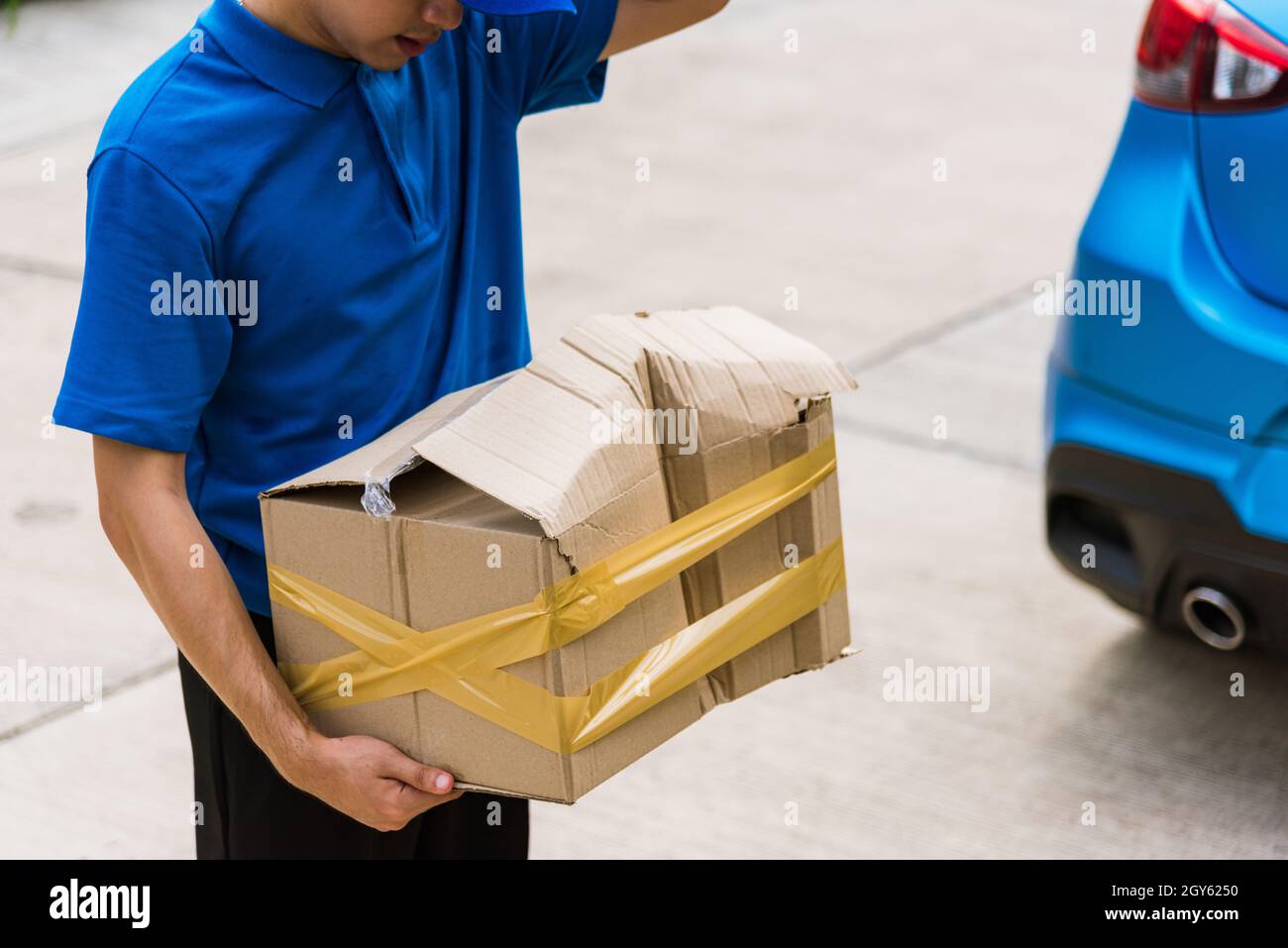 Asian young delivery man in blue uniform he emotional falling courier ...