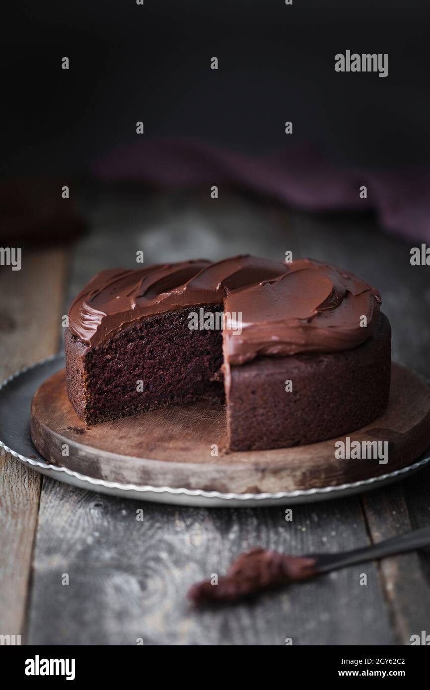 A frosted chocolate cake with a slice missing Stock Photo - Alamy
