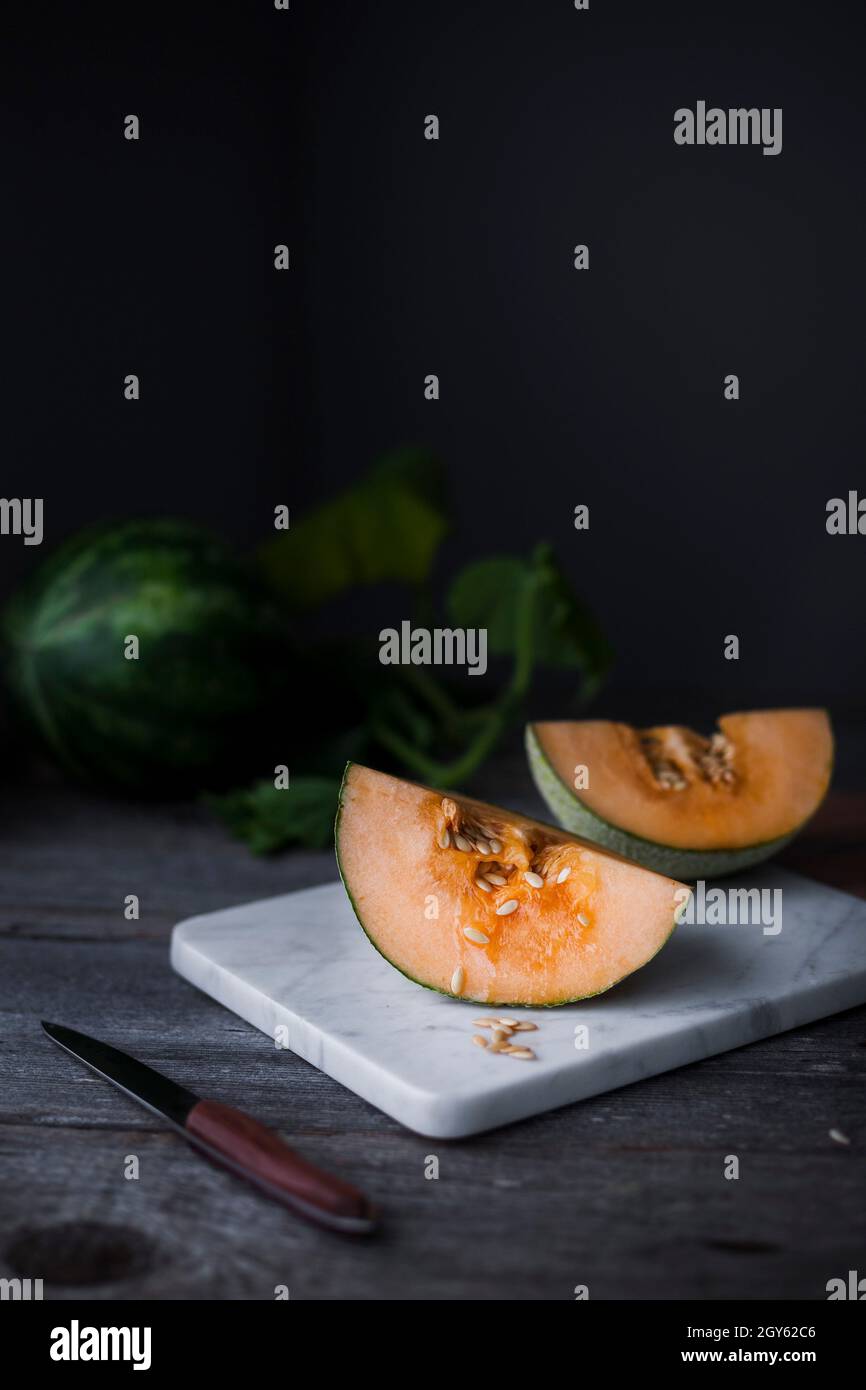 A quartered cantaloupe melon on a marble chopping board Stock Photo - Alamy
